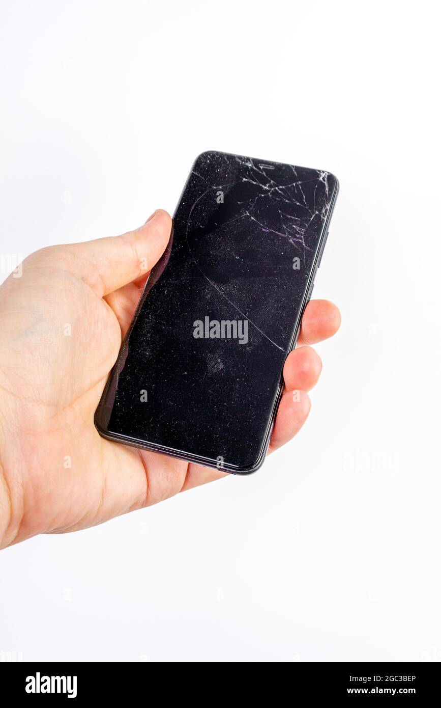 Hand holding a black smartphone with a damaged screen Stock Photo - Alamy