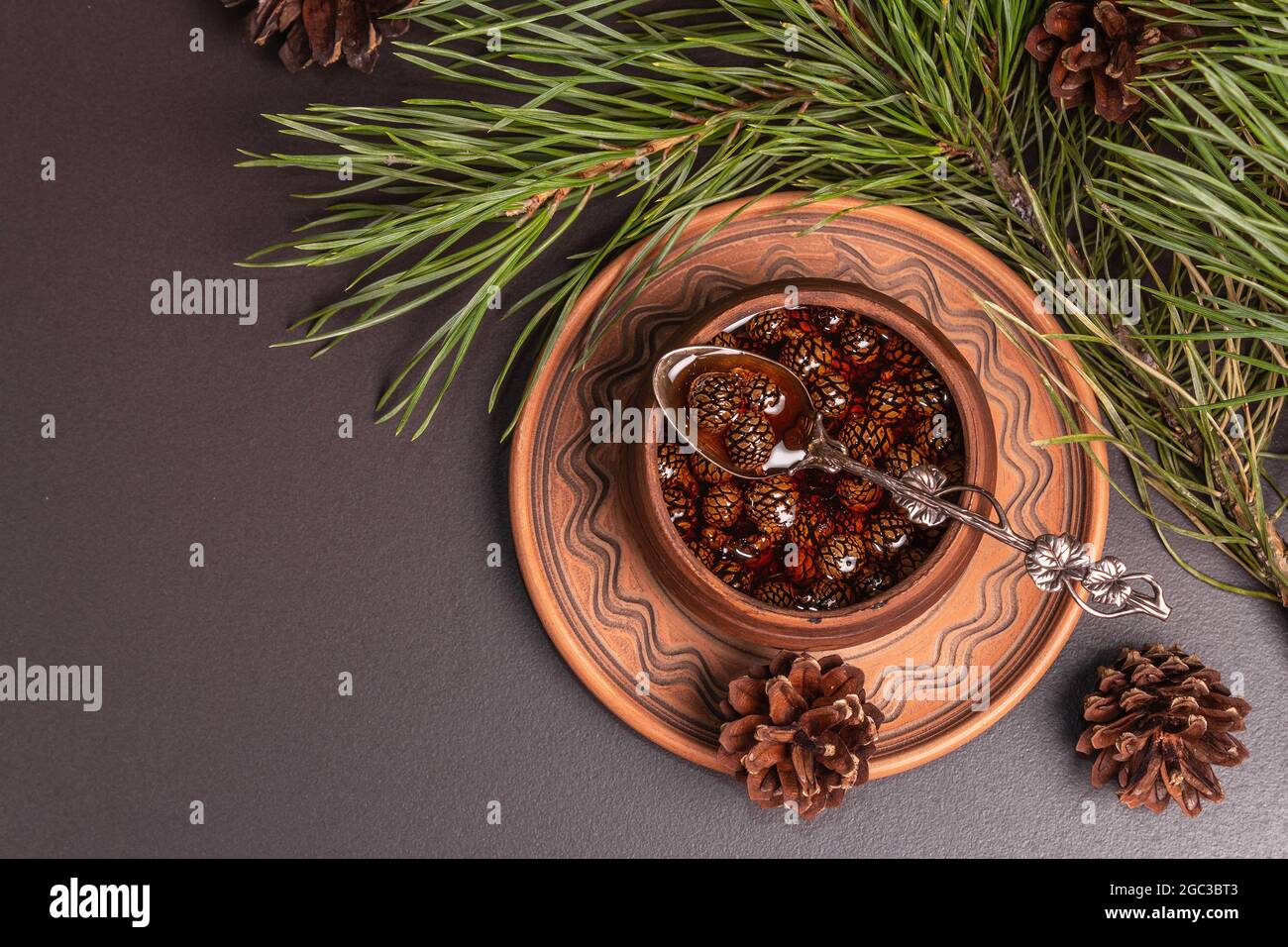 Sweet pine cone jam. Traditional Siberian dessert, fresh evergreen branches. Black stone ...
