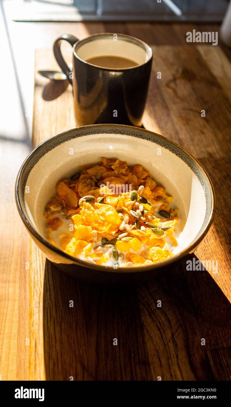 Breakfast cornflakes with seeds and milk and mug of coffee in kitchen ...