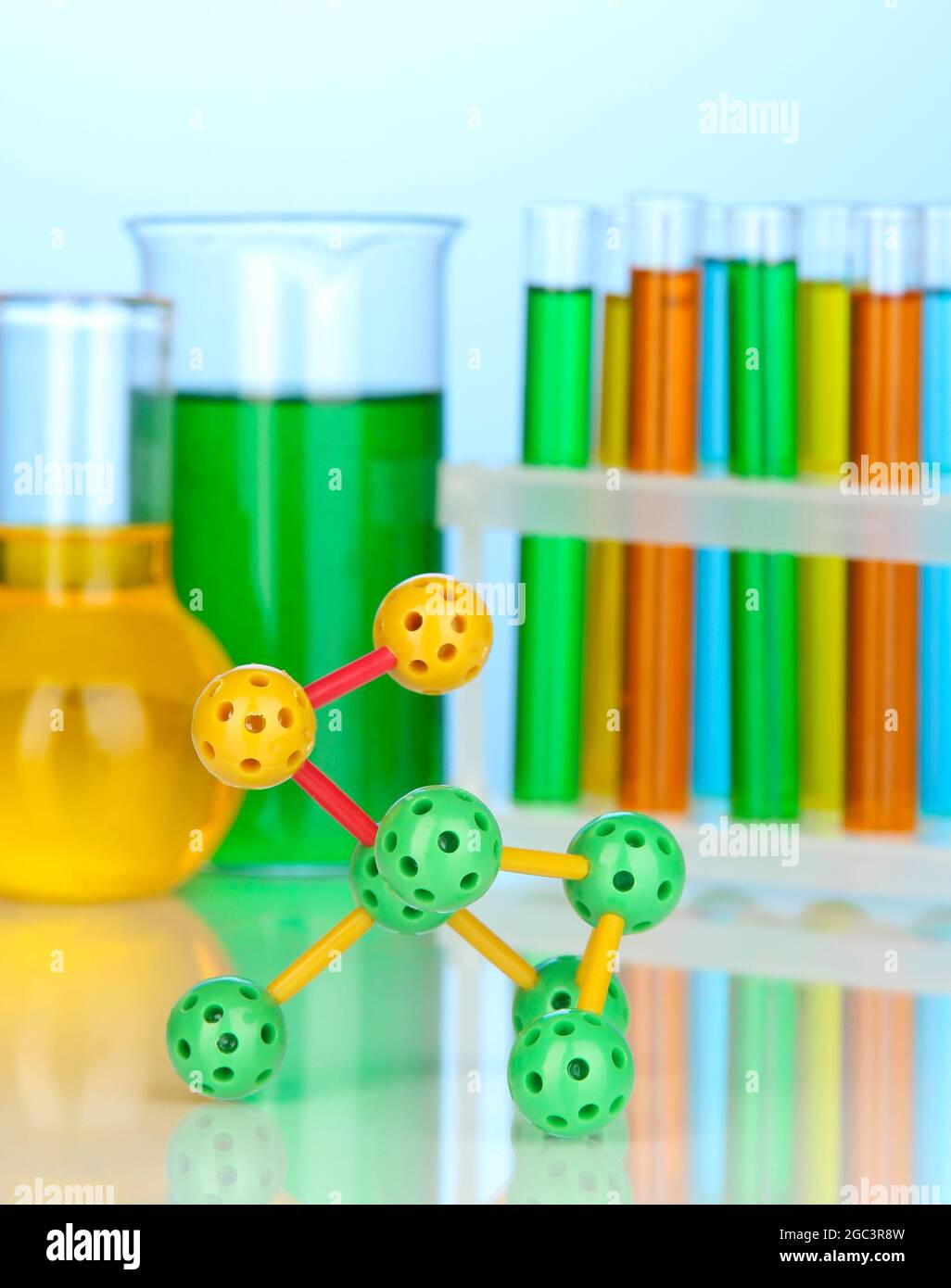 Molecule model and test tubes with colorful liquids on blue background ...