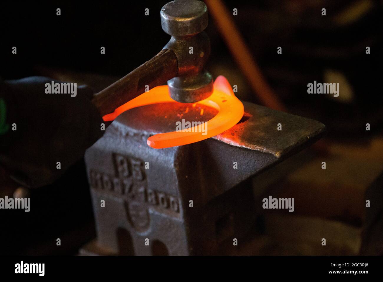 Hard work in the smithy on the anvil. Hammering glowing steel horse ...