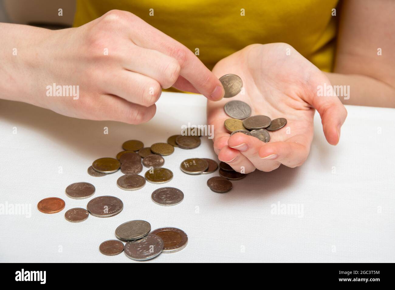Saving money, a hand puts coins in another hand, on a light table are ...