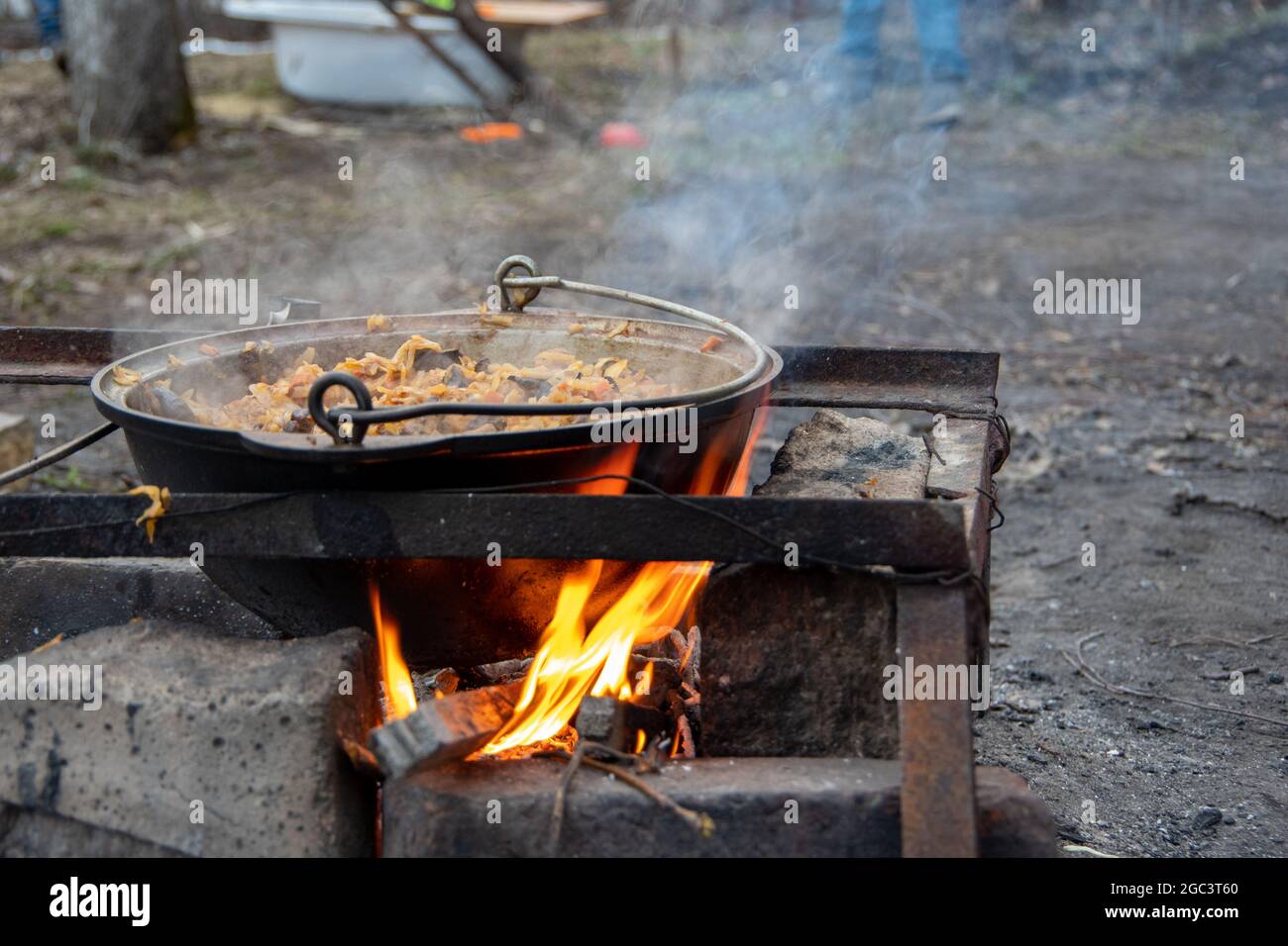 Cooking meat with vegetables in a large cauldron, street food outdoors ...