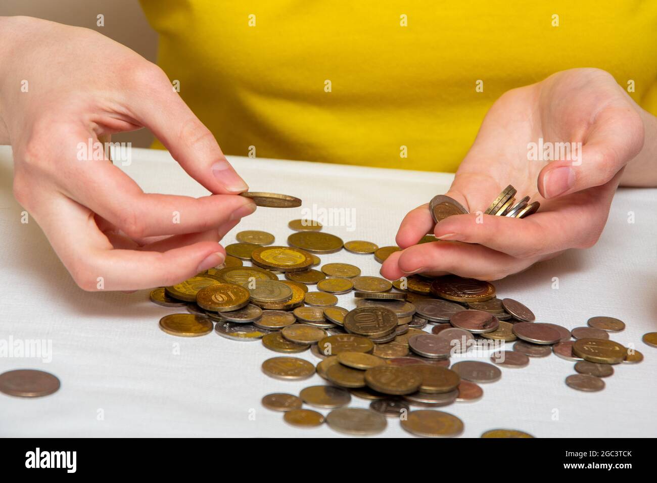 Saving money, a hand puts coins in another hand, on a light table are ...