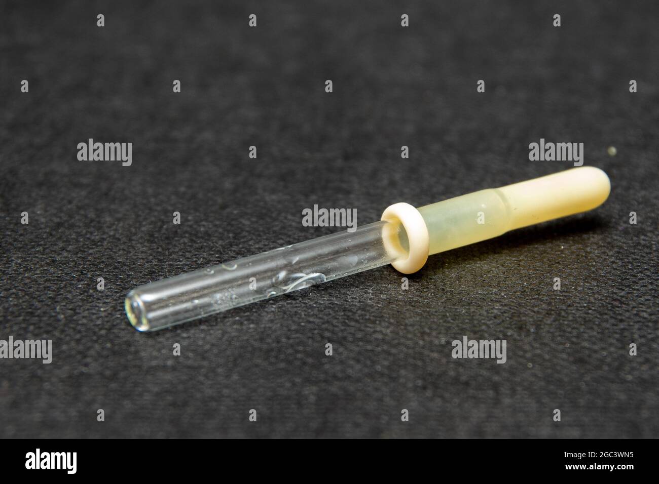 glass dropper with a yellow rubber tip on a black background close-up ...