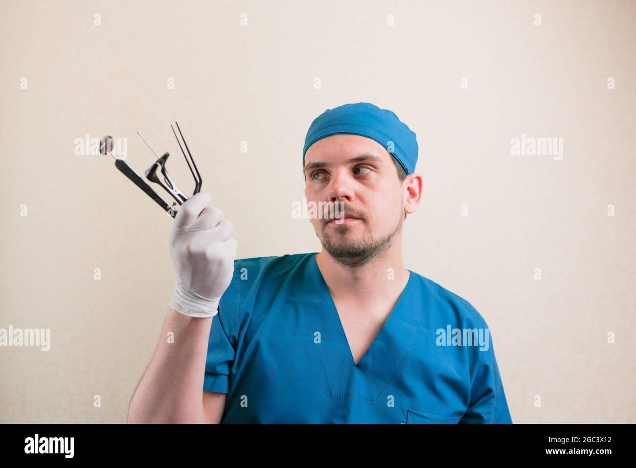 Young smiling doctor with medical instruments in his hand in blue ...