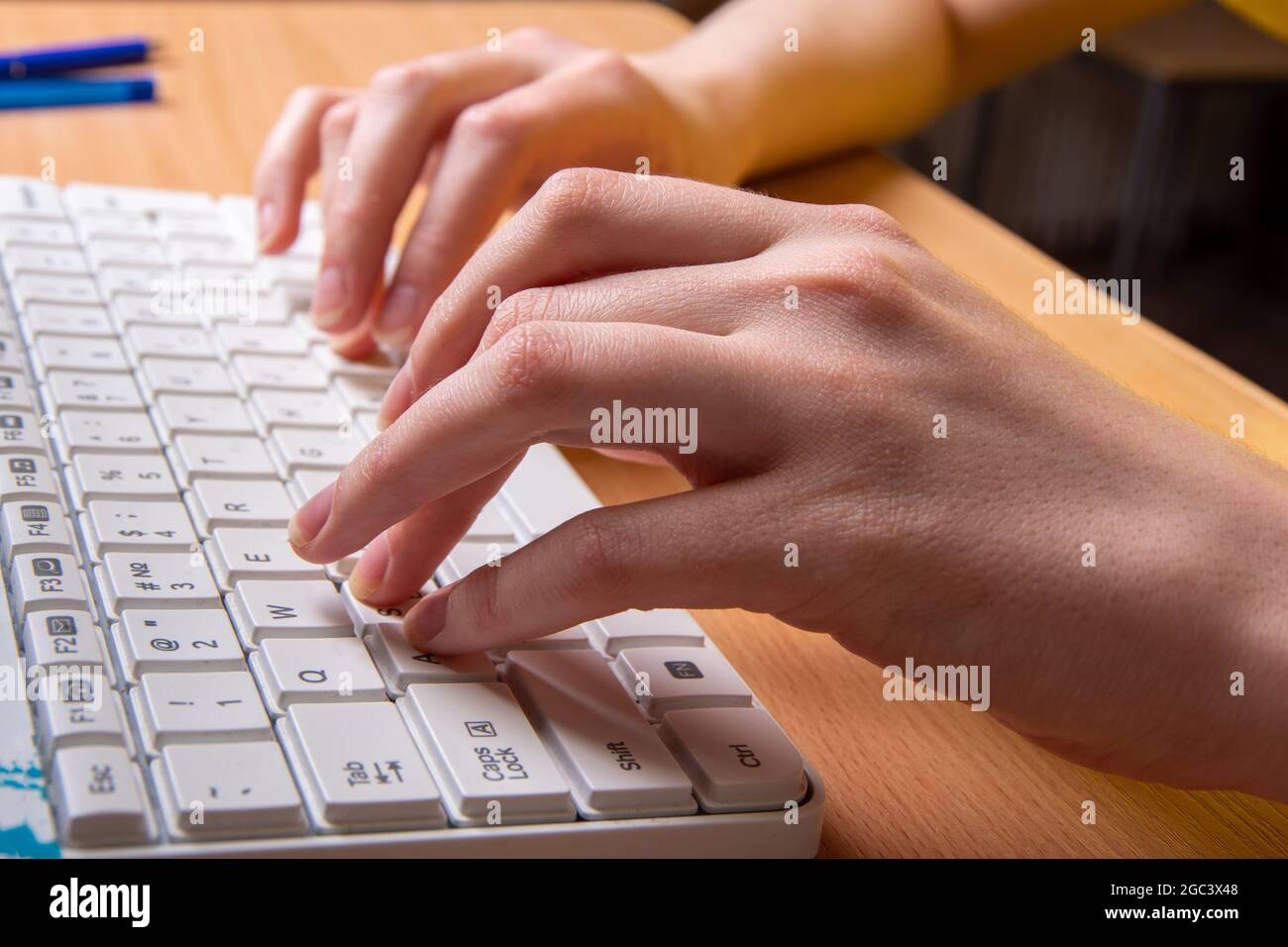 two female hand is typing on a white keyboard with English letters ...