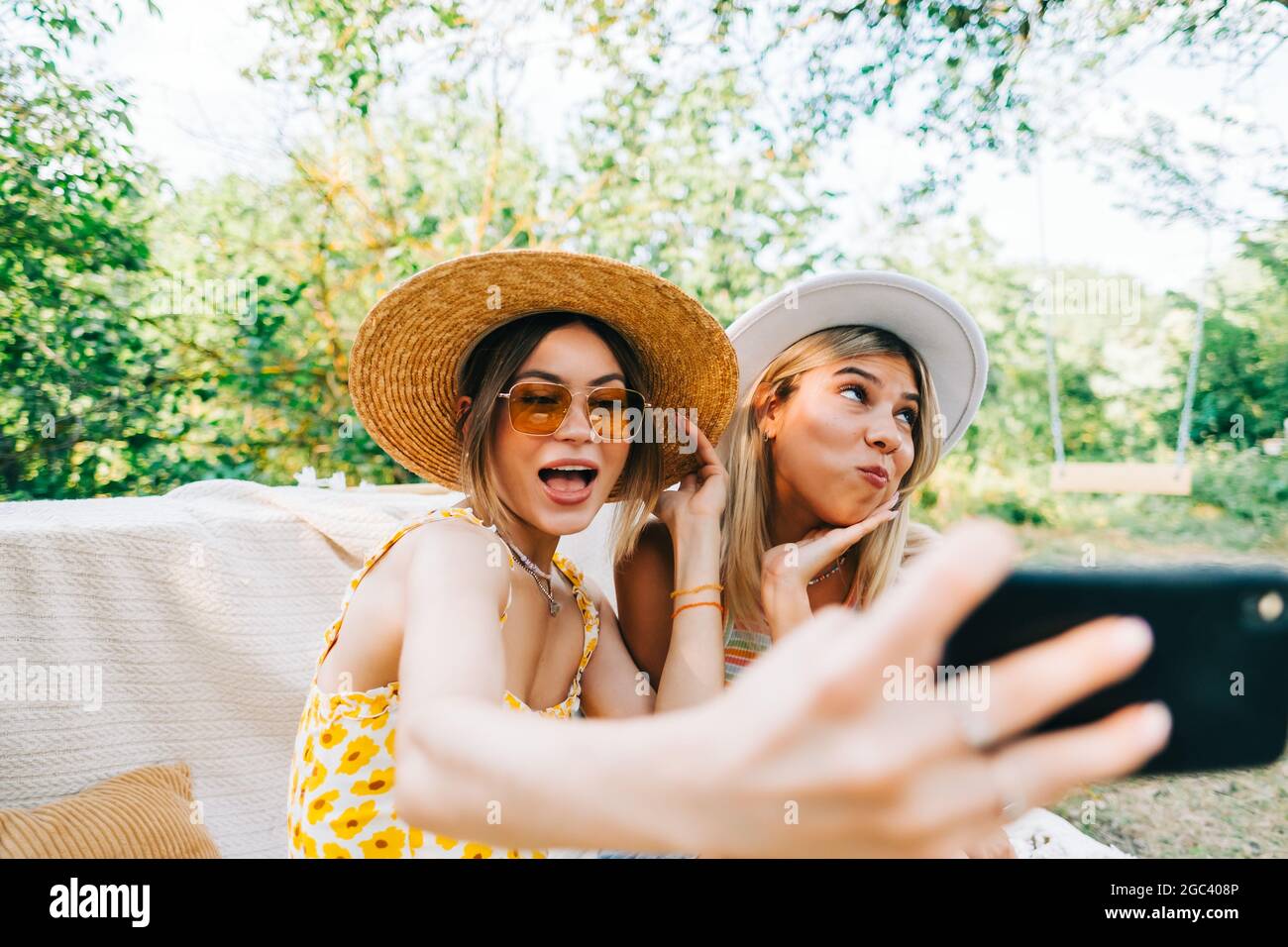 Two young cheerful women having fun and making photo outdoor in the ...