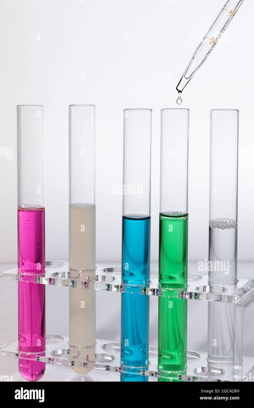 Laboratory test tubes with colorful reagents and pipette with drop ...
