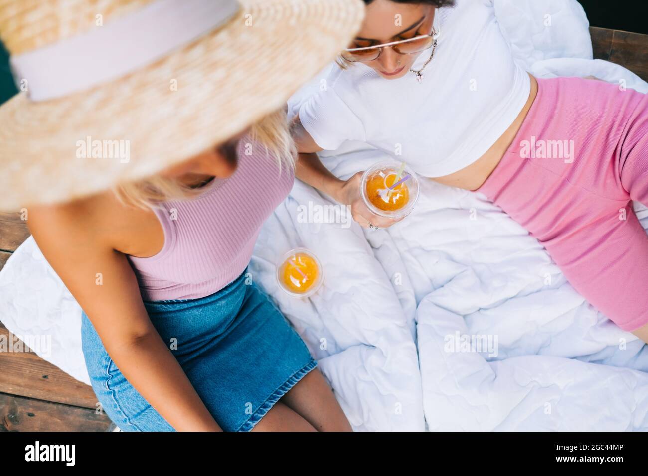 Two attractive women friends resting outdoor on lake pier, lying on ...