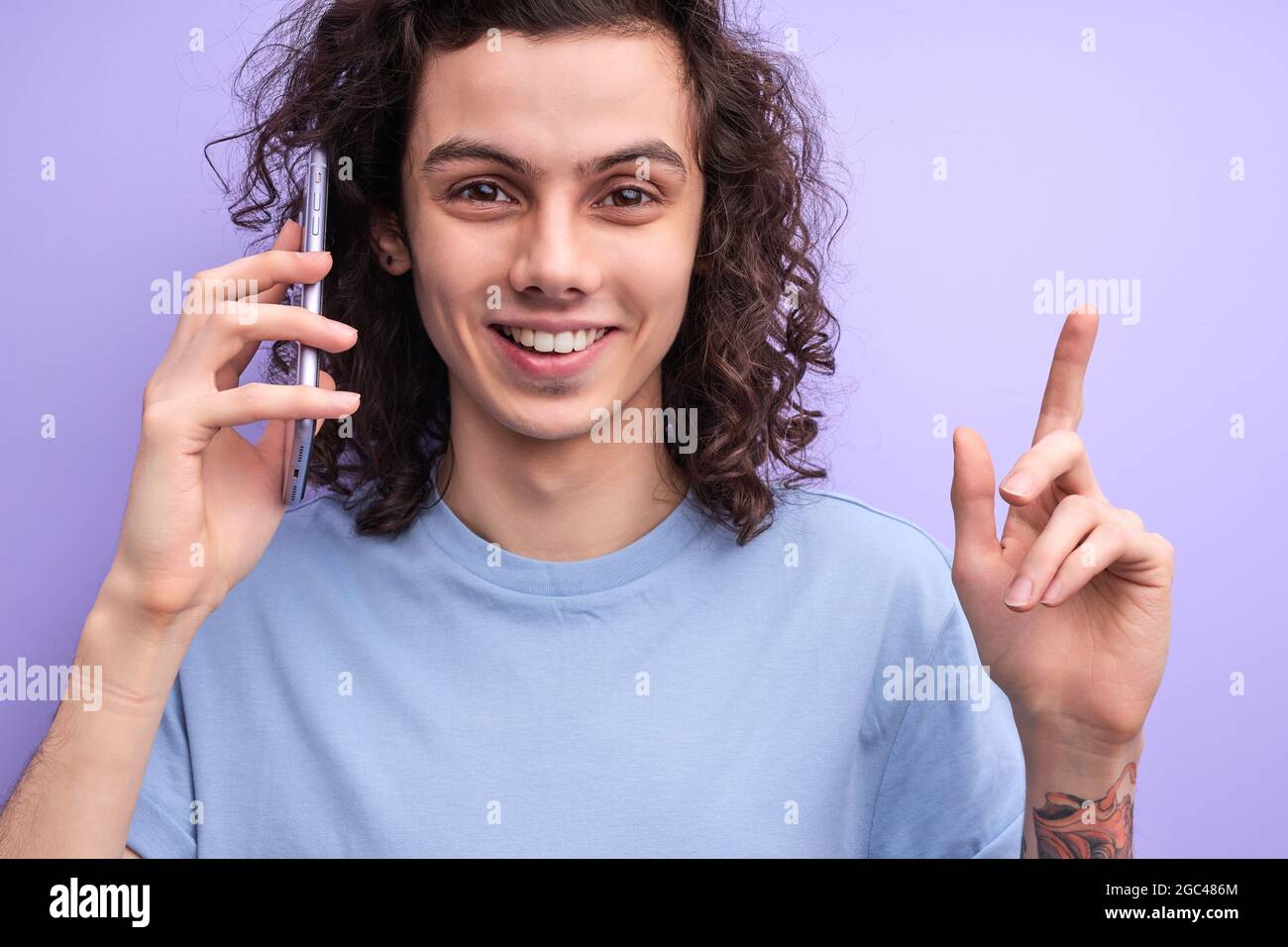 Positive male has an idea, raising finger up while talking on phone ...