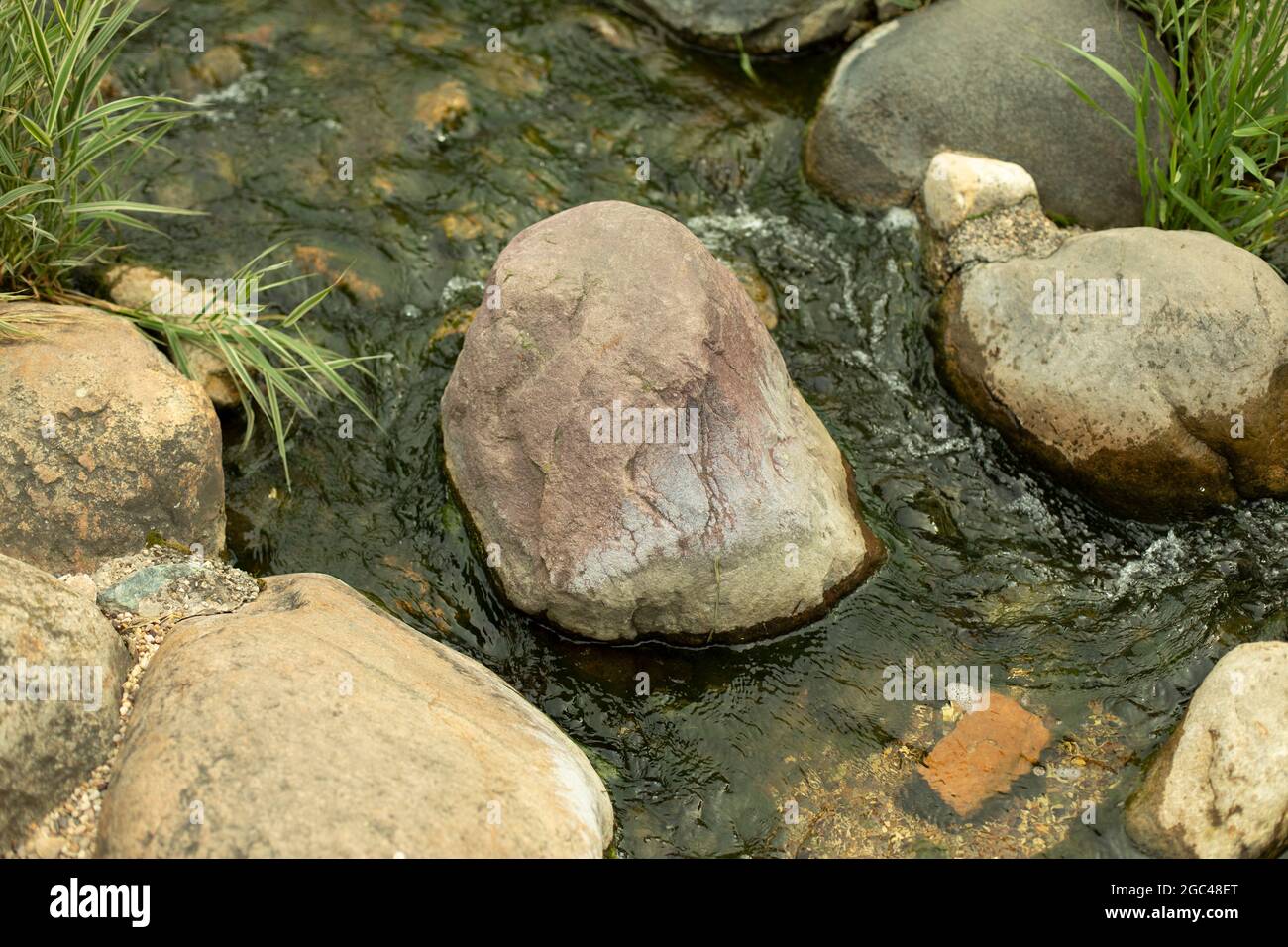 Water runs over the stones. Fresh water stream. Artificial waterfall ...