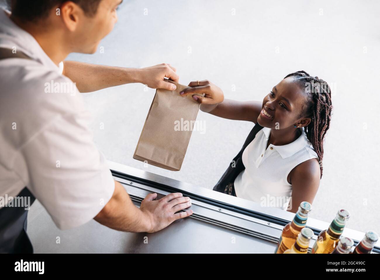Woman receiving meal from a food truck in city. Young smiling female ...