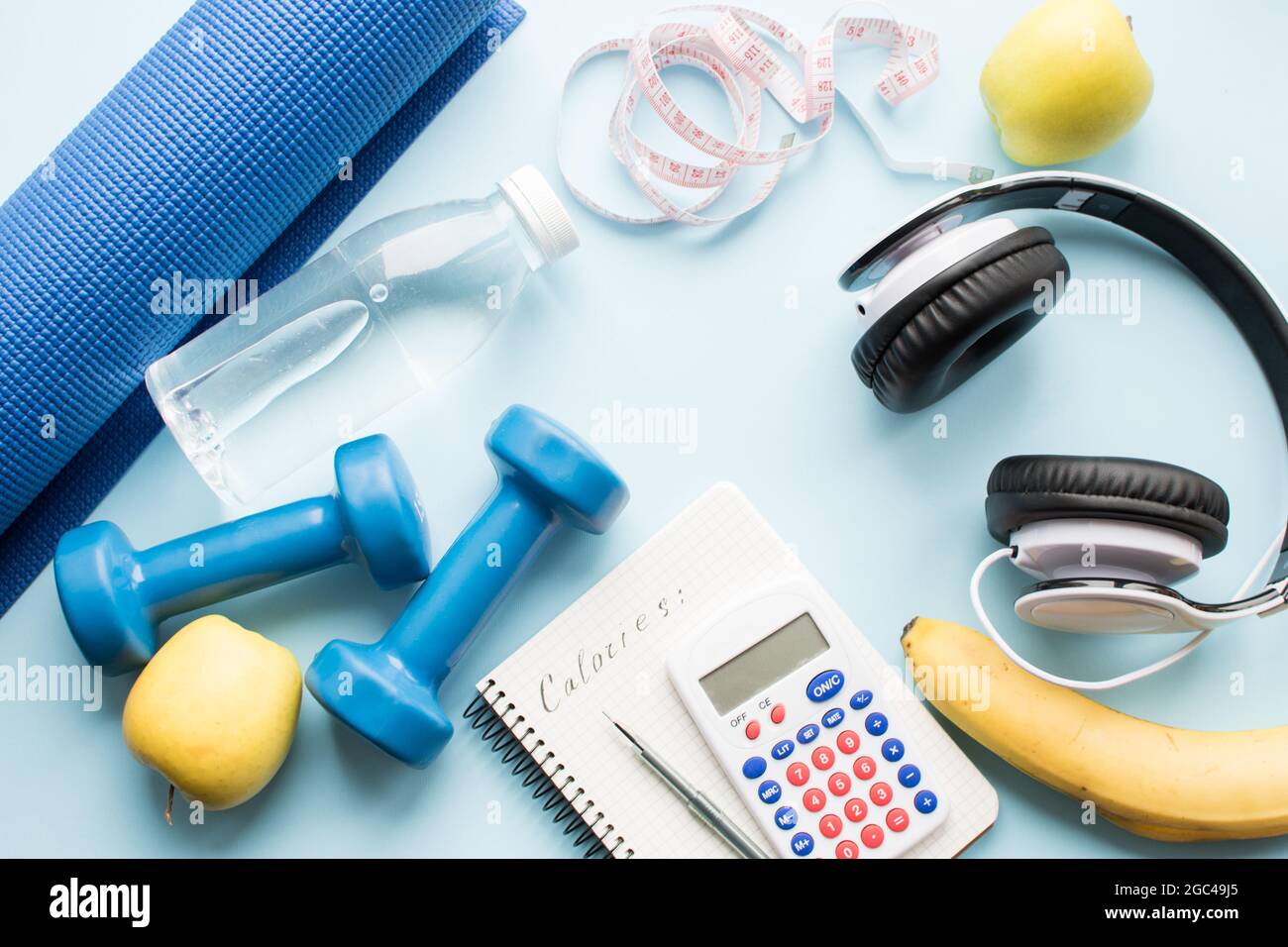 Paper notebook, calculator, pen, dunbbell and fruits on blue background ...