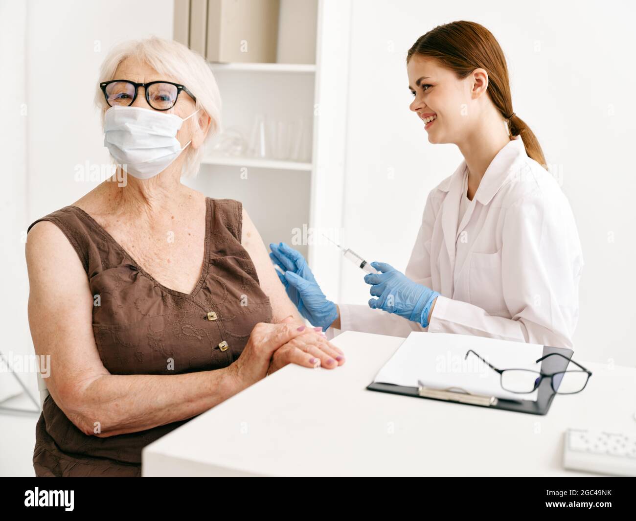 Nurse giving injection to elderly woman patient immunization safety ...