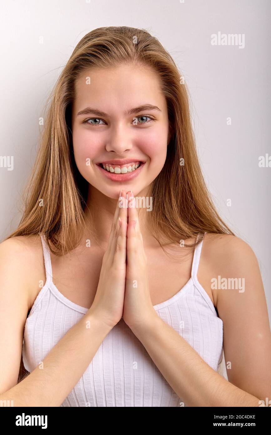 Portrait of positive teen girl keeping hands together looking at camera ...