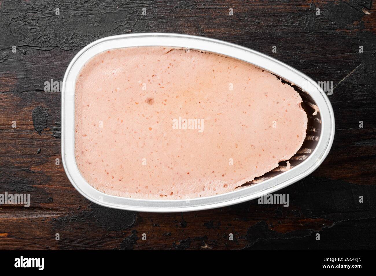 Chicken pate in opened aluminum packaging set, on old dark wooden table ...