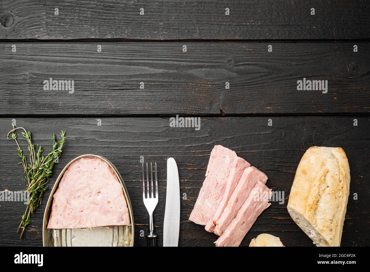 Open pork luncheon meat can with baguette set, on black wooden table ...