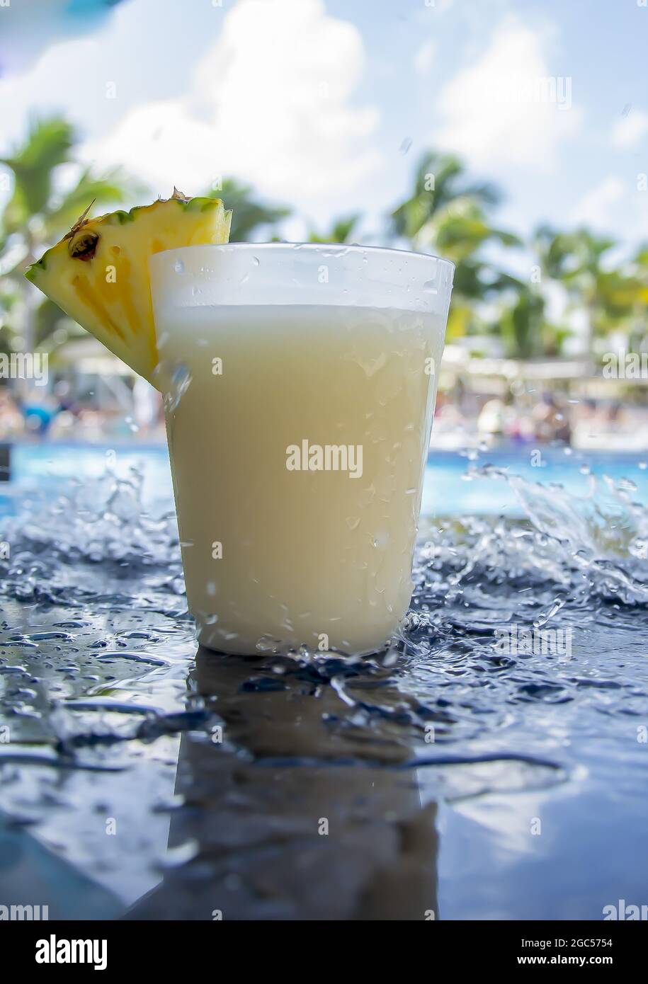 Vertical shot of pina colada cocktail by the side of a tropical pool ...