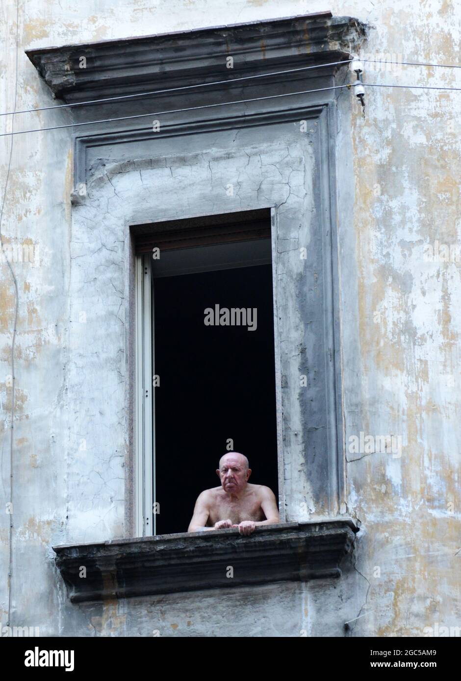 An elderly Italian man looking out the window from his home on Via ...