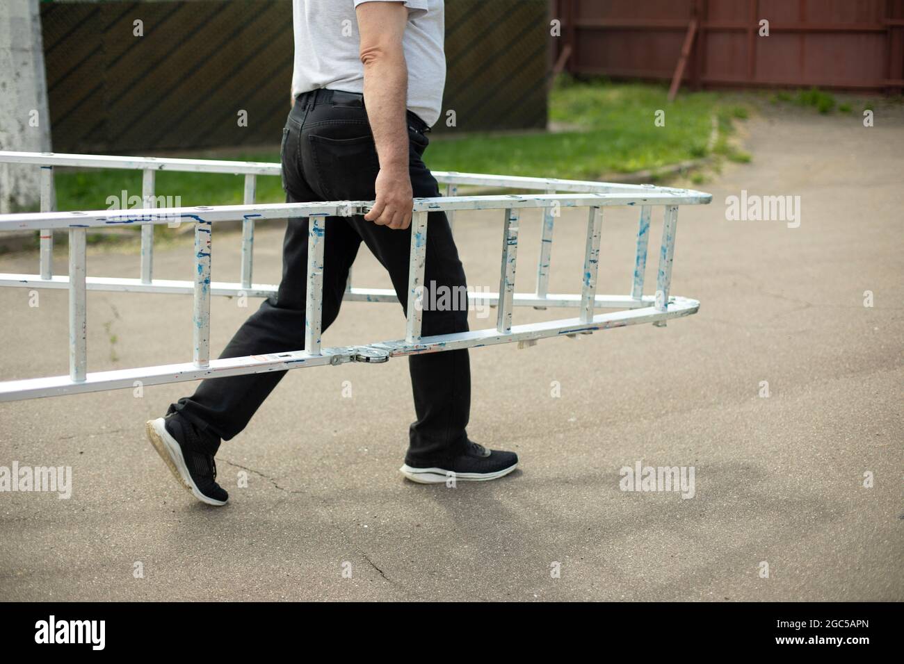 A man carries a ladder. The guy's dragging the ladder. The gardener ...