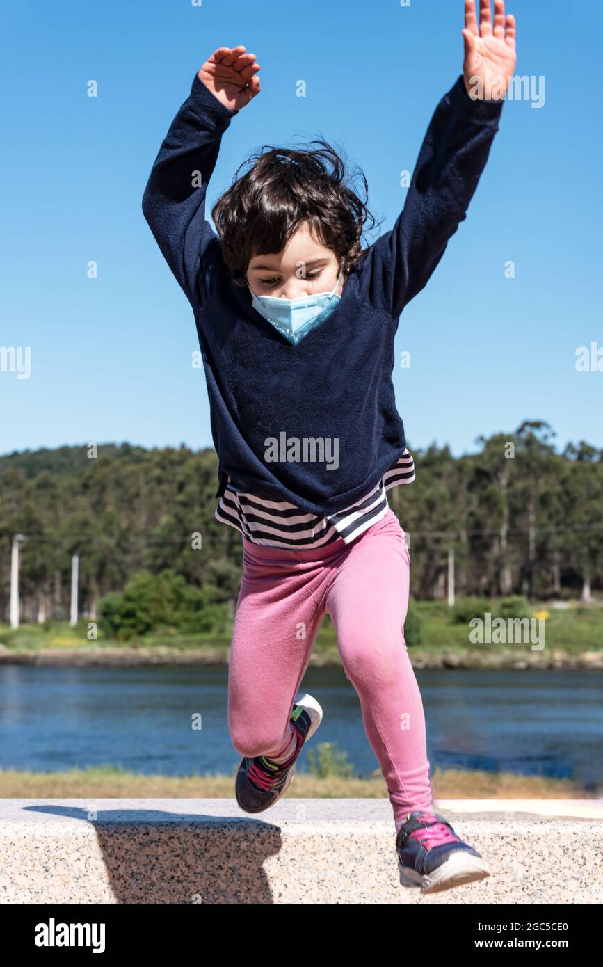 caucasian child jump at grass from the bench on the promenade with ...