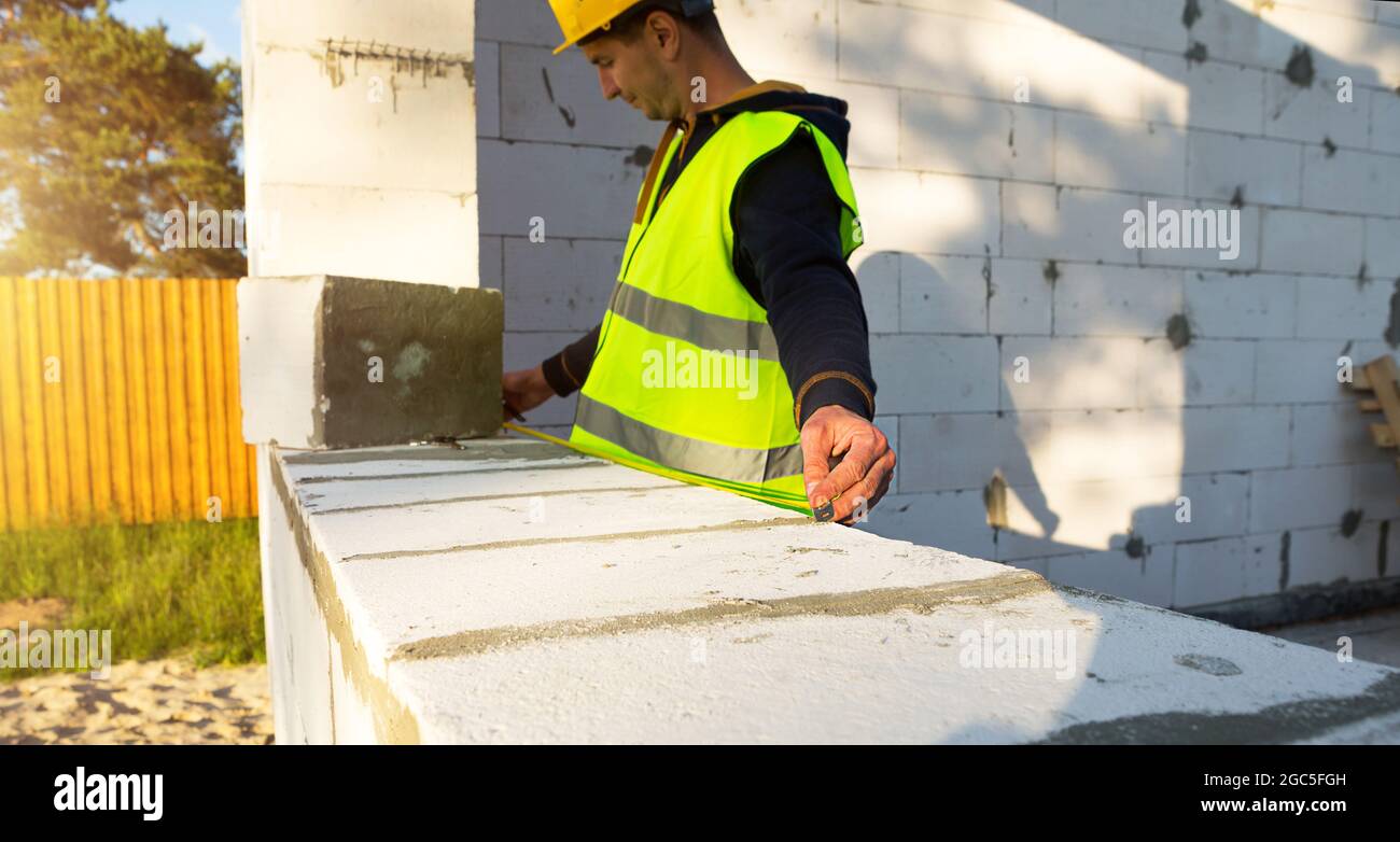 Construction worker at construction site measures the length of the ...