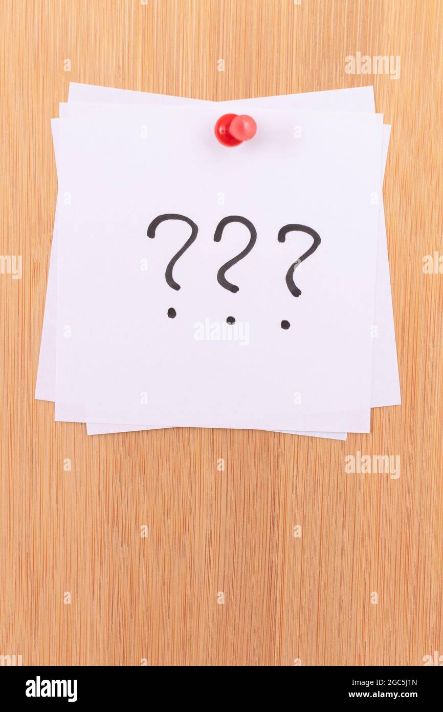 White Sticky Notes with Three Question Marks Pinned to the Wooden ...