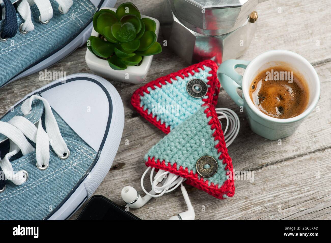 Cute knitted ear pods holder on wooden table. Lifestyle set with cup of ...