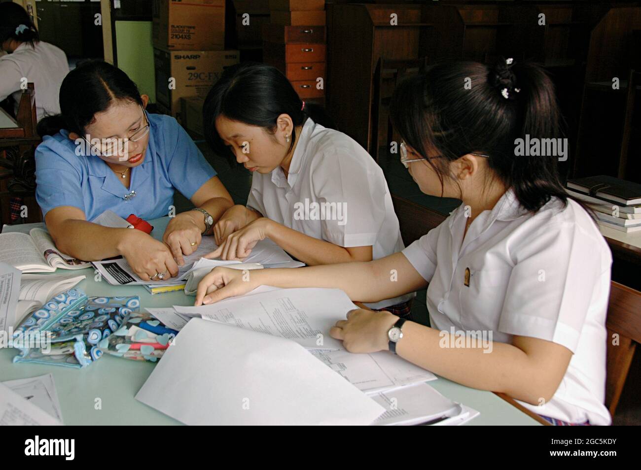 A teacher are discussing a lesson with two high school students Stock ...