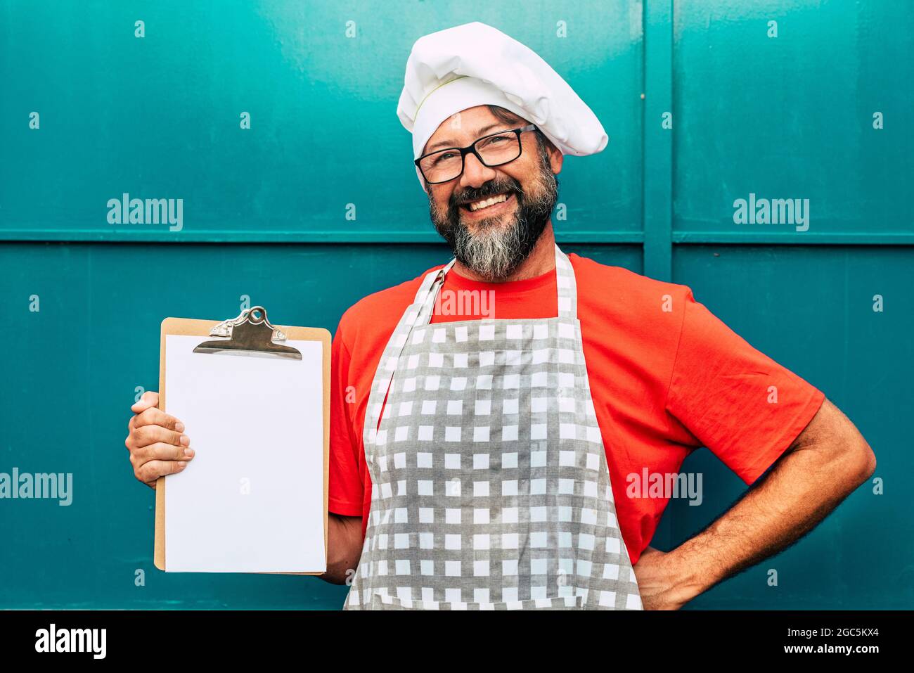 Cheerful happy man chef outside closed restaurant use a white empty ...