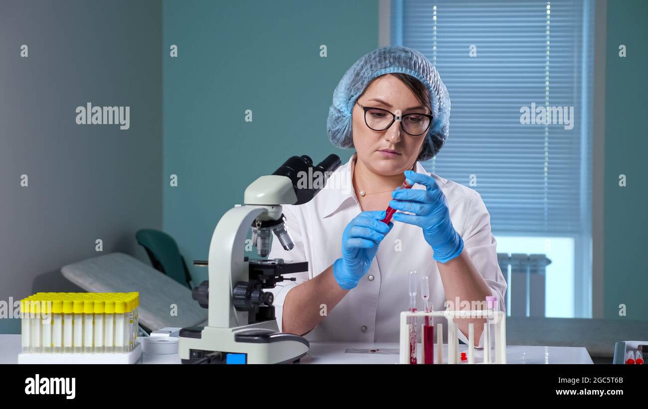 Lab assistant shakes test tube with red liquid in hospital Stock Photo ...