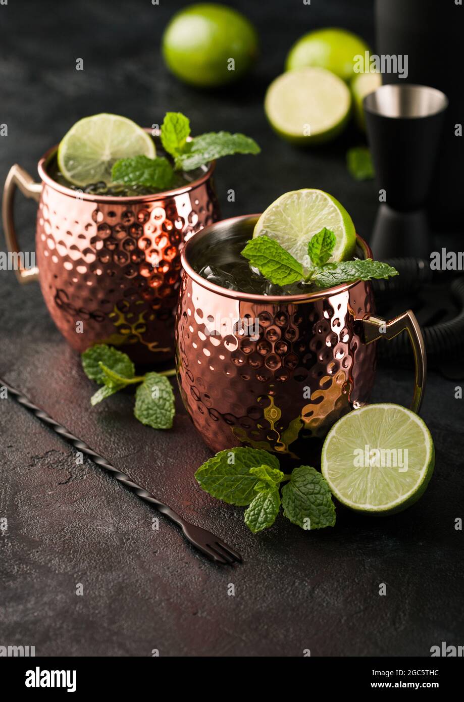 Moscow mule cocktail in a copper mug with lime and mint and wooden ...
