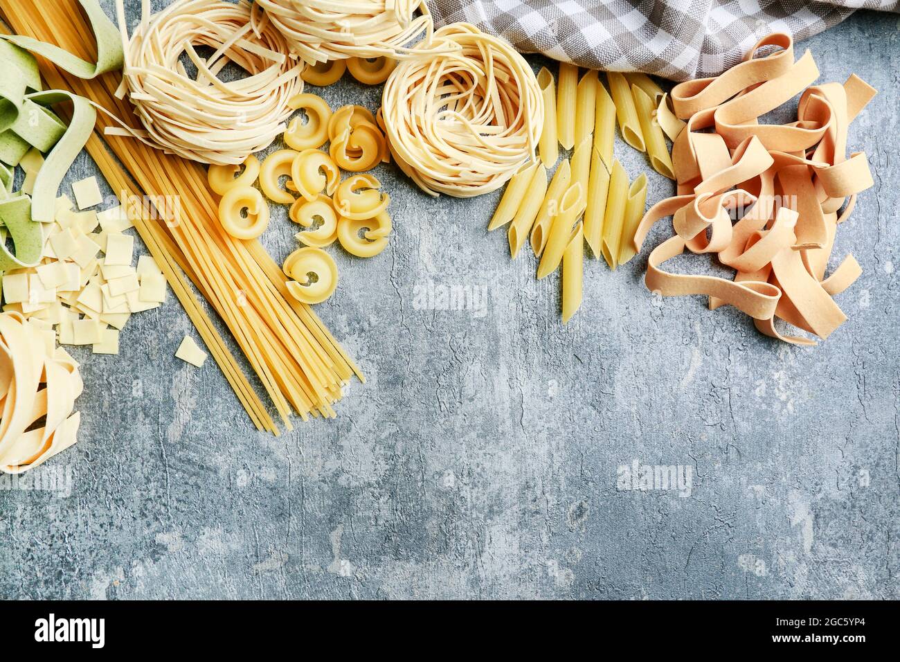 Mixed types and shapes of italian pasta on grey stone background. Copy ...