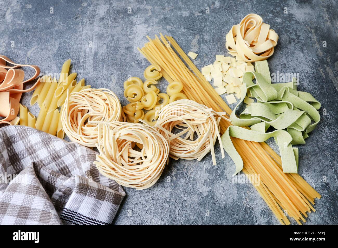 Mixed types and shapes of italian pasta on grey stone background. Copy ...
