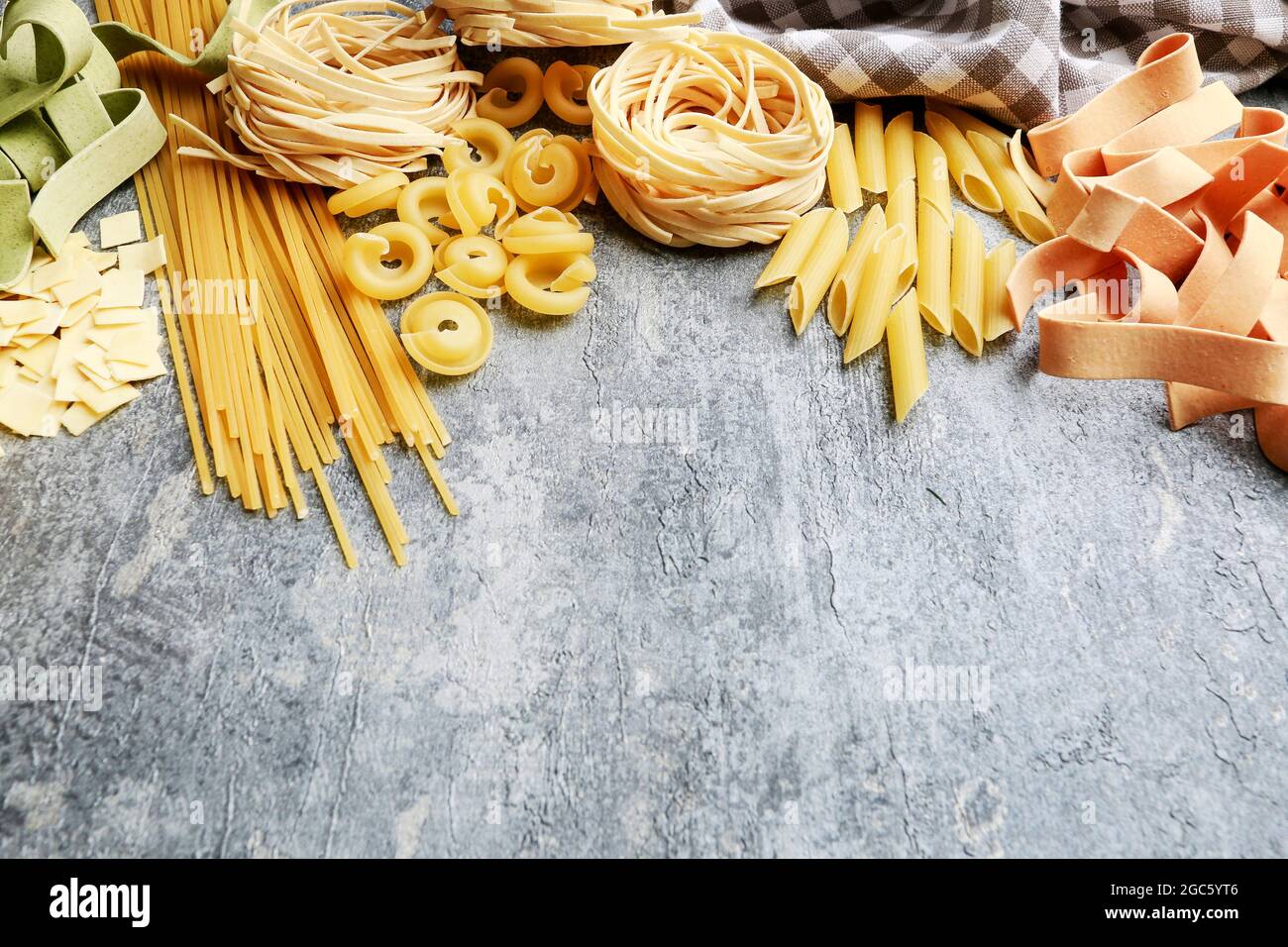 Mixed types and shapes of italian pasta on grey stone background. Copy ...
