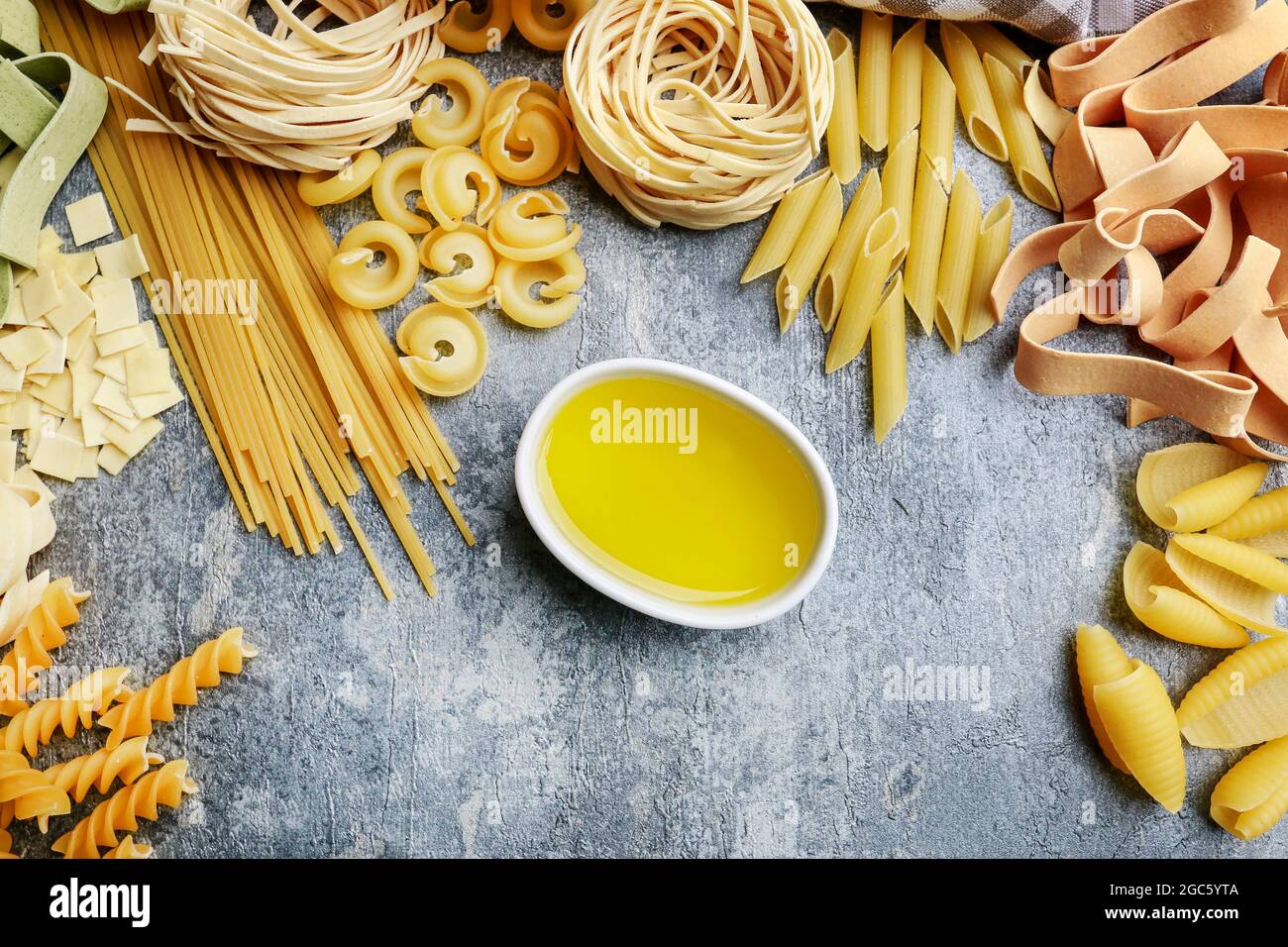 Mixed types and shapes of italian pasta on grey stone background. Copy ...