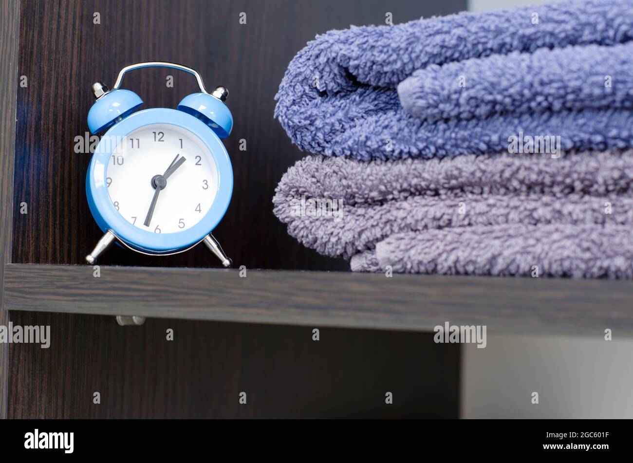Blue alarm clock on the shelf with bath towels. Massage time Stock ...