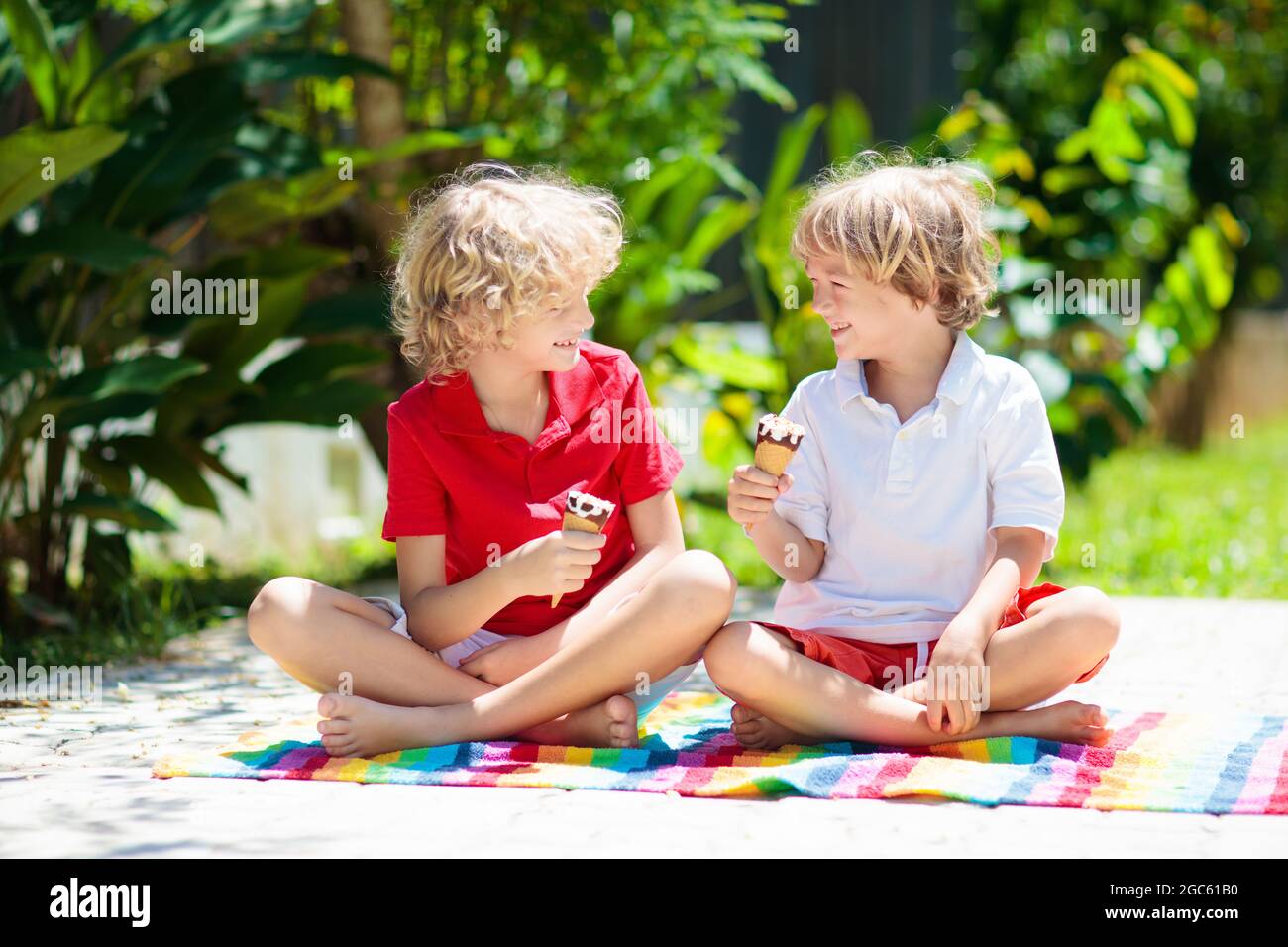 Kids eat ice cream in garden. Summer outdoor fun. Children lick ice ...
