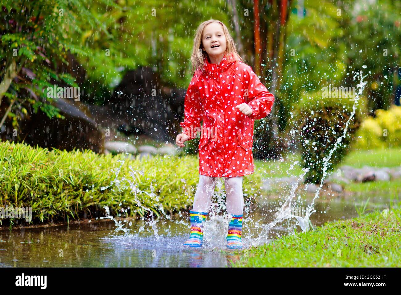 Child playing in puddle. Kids play and jump outdoor by autumn rain ...