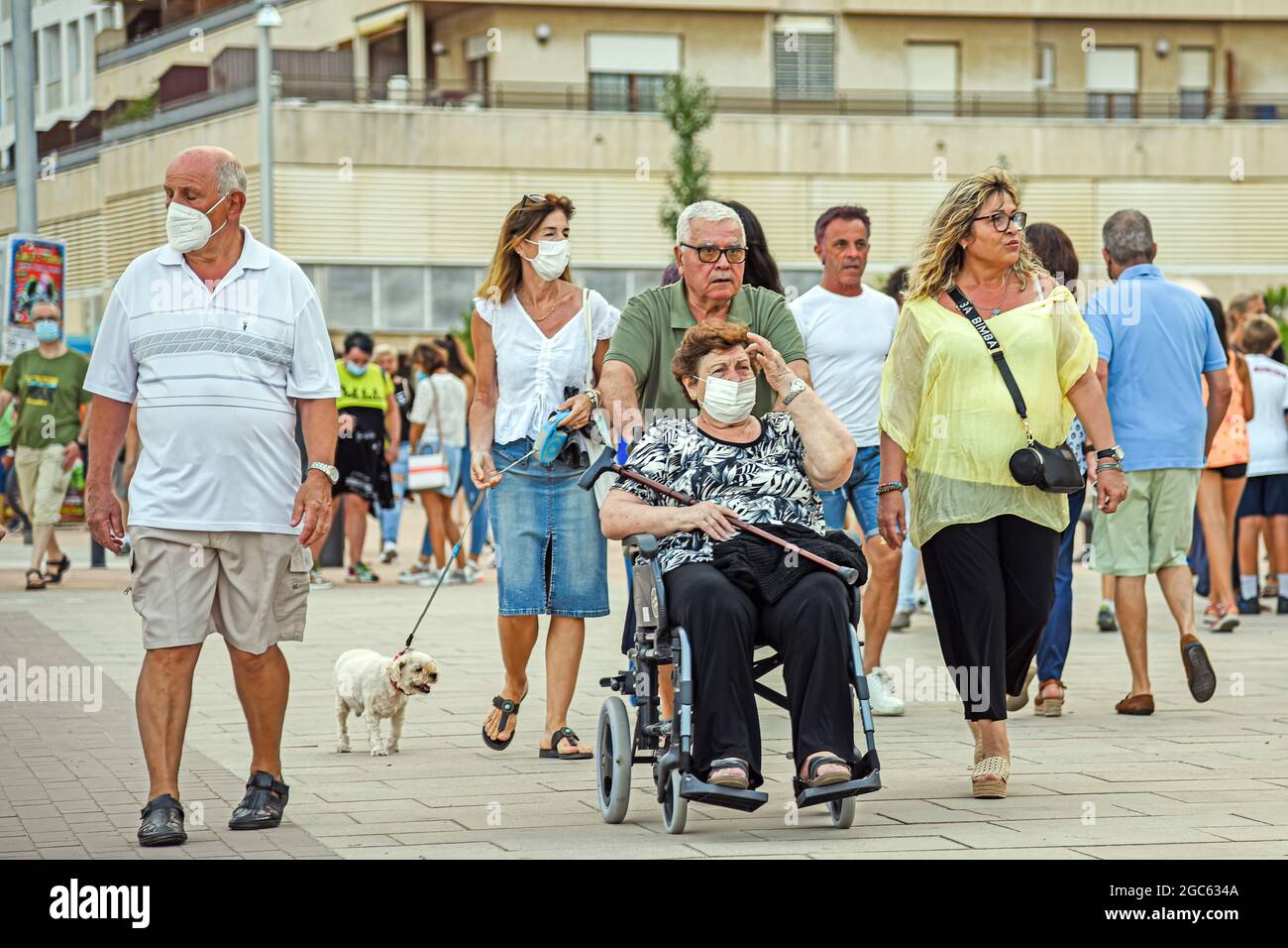 Elderly people with and without face masks, walk in the maritime ...