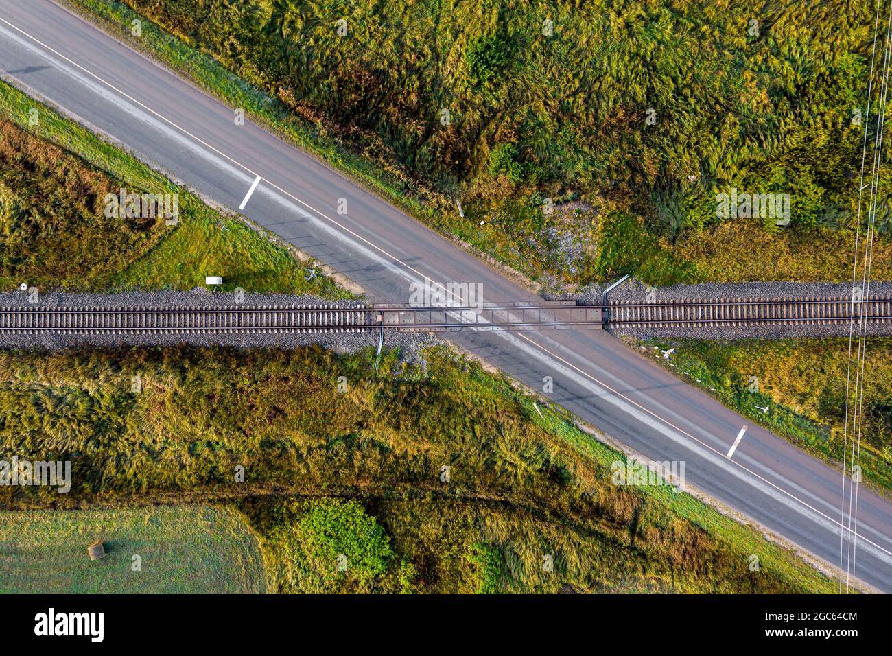 aerial view of railroad tracks crossing a asphalt road in rural area ...
