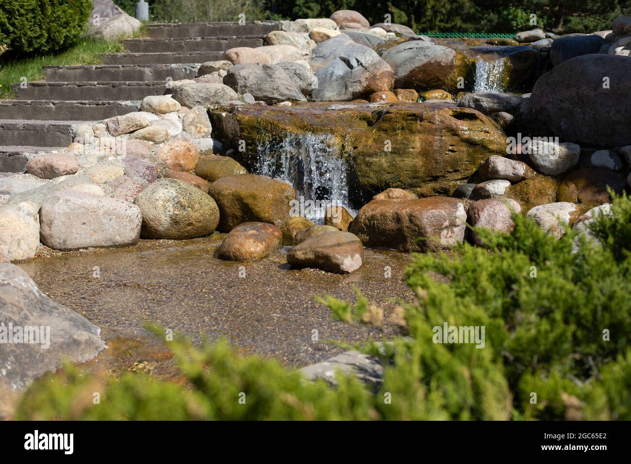A stream among the stones in the park. Landscaping. Artificial alpine ...