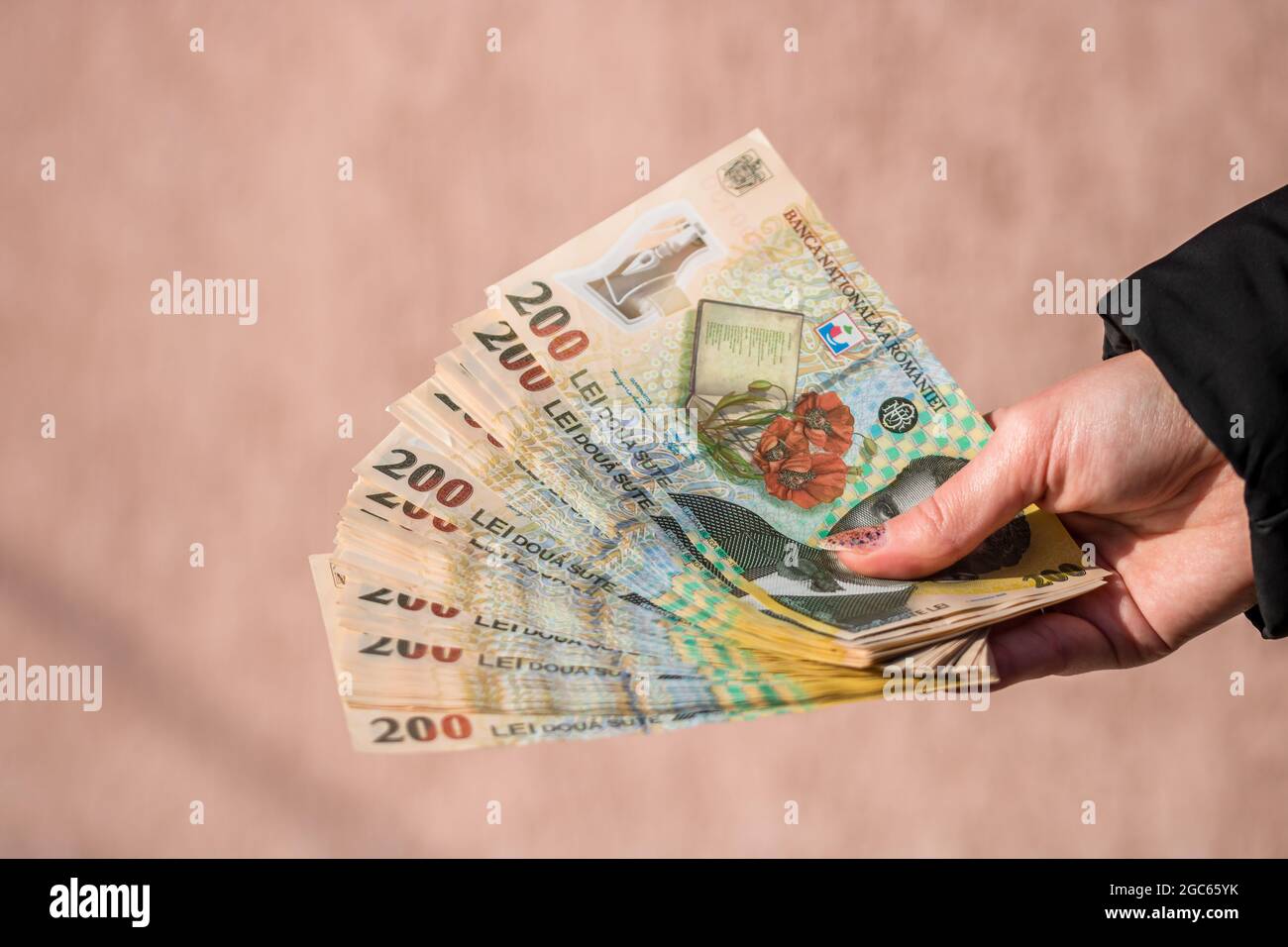 Shallow focus shot of a hand with 200 Romanian Leu banknotes on a pinky ...