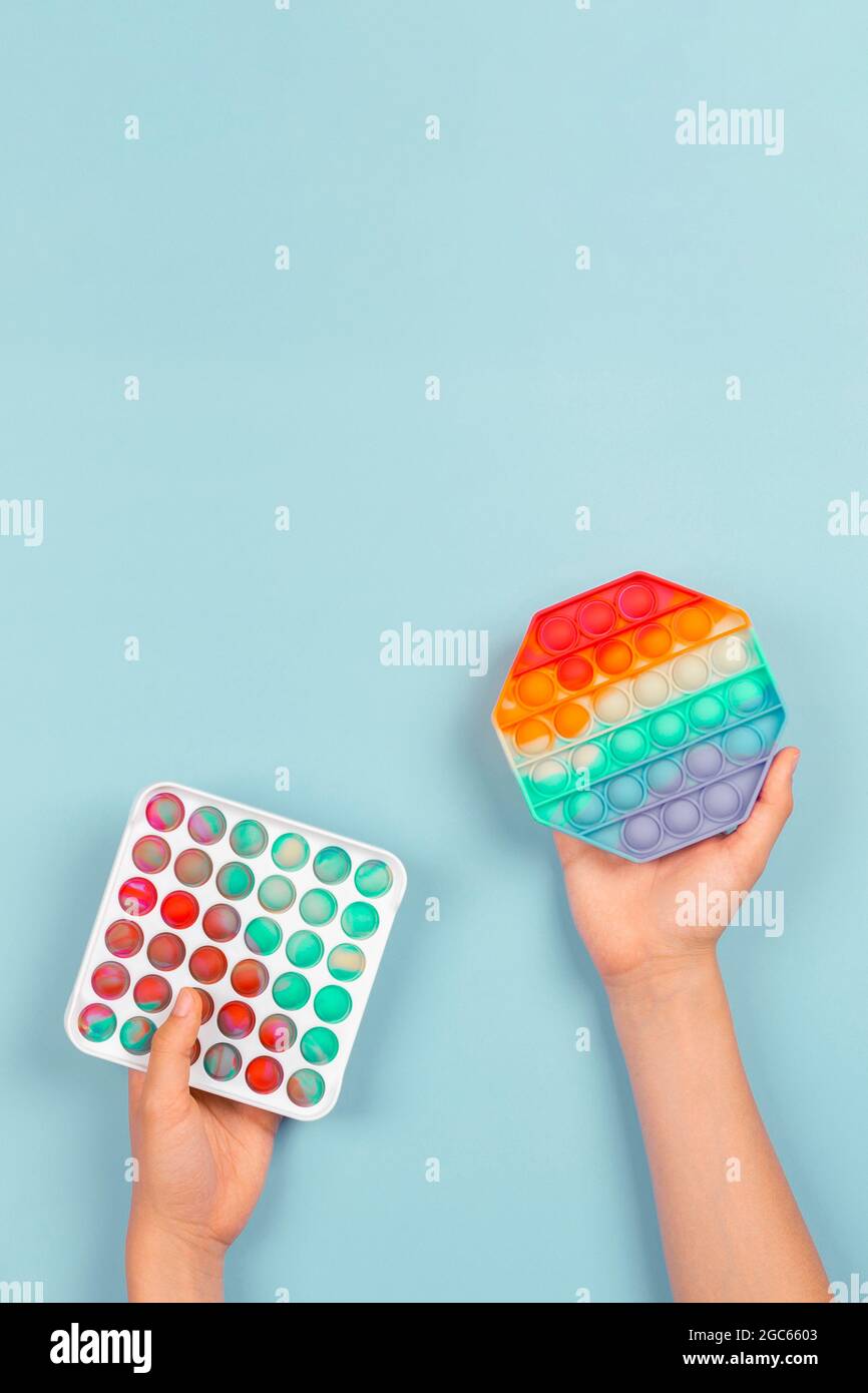 Hands holding pop it fidget toys on blue background. Push pop-it ...