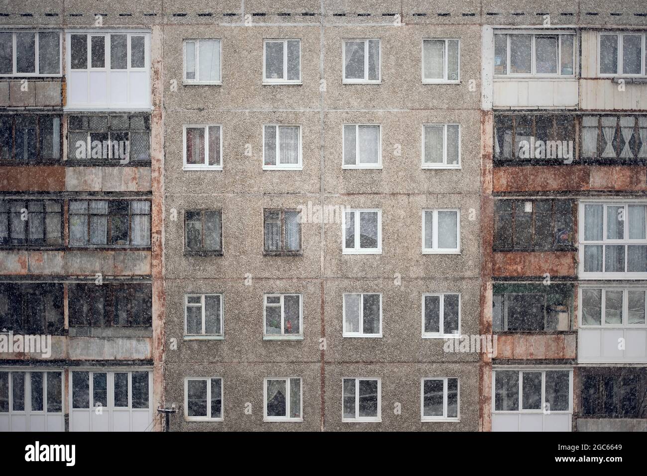 Facade of a grey multi-storey soviet panel building in the fallen snow ...