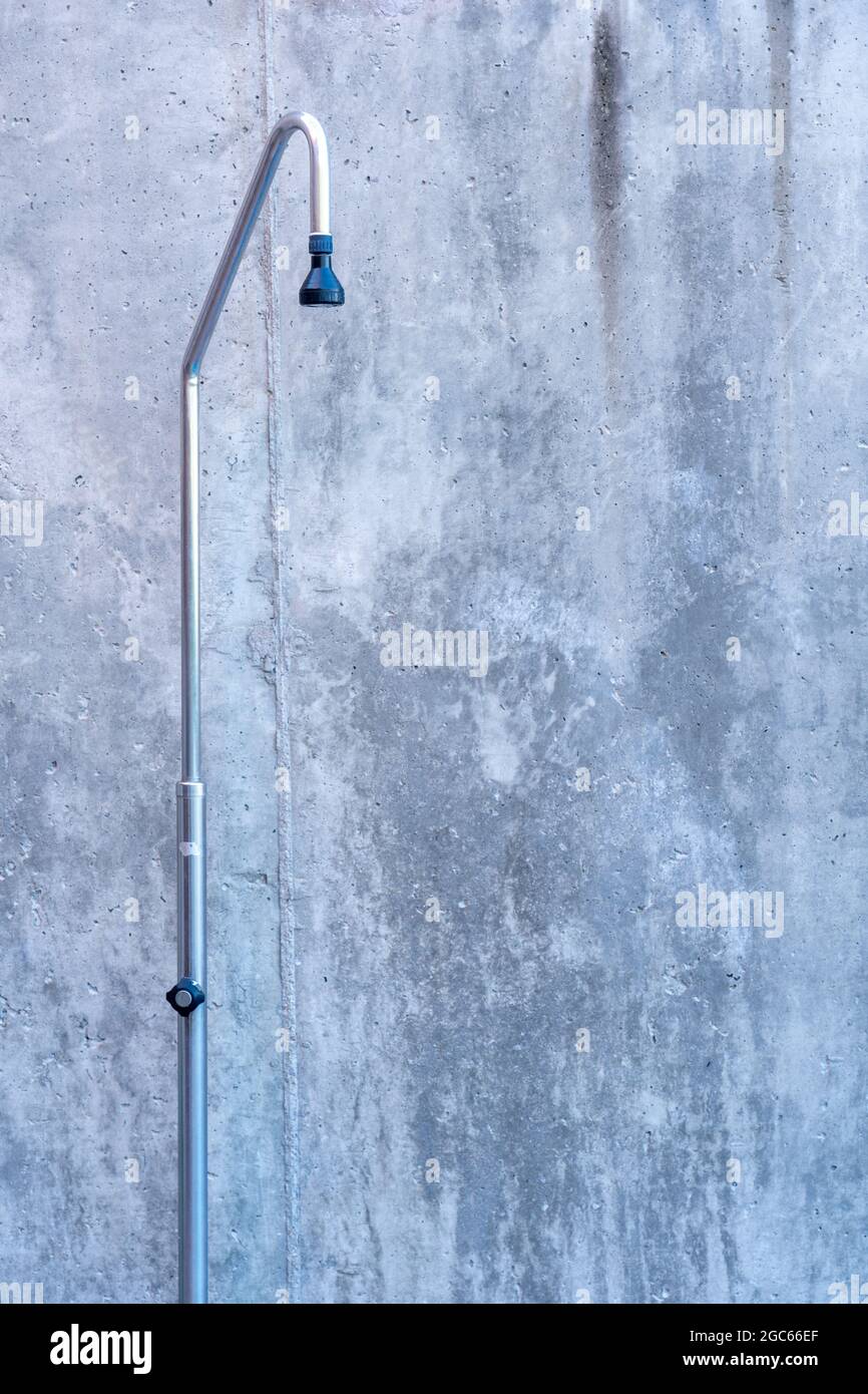 Vertical shot of a thin shower with the pipe fixed on gray wall Stock ...