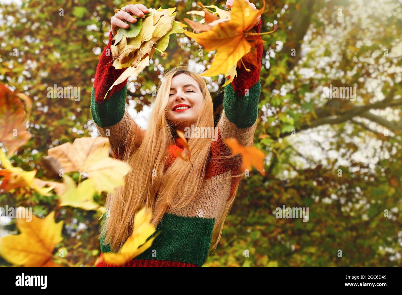Joyful girl throws leaves in autumn park. Woman feel good outdoors in ...
