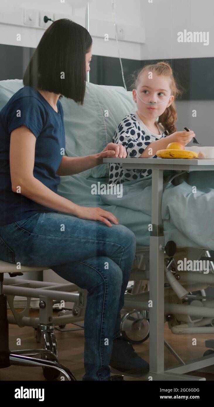 Sick child patient sitting in bed with oxygen nasal tube eating healthy ...