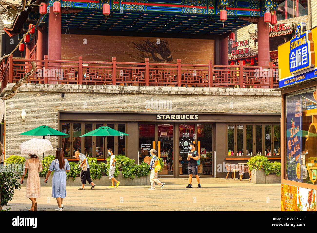 Yangshuo, China. 25th July, 2021. People walk past a Starbucks ...